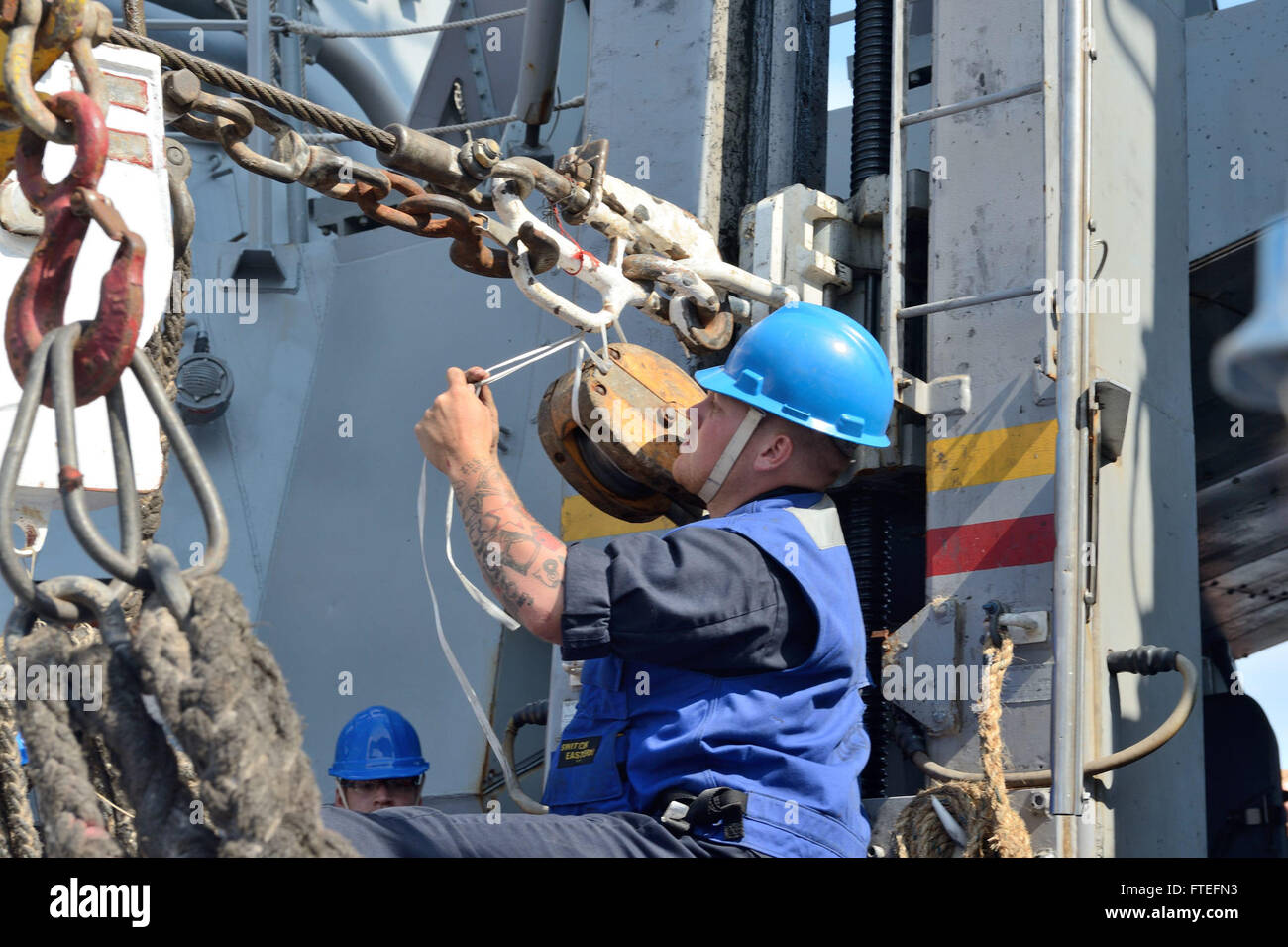 The image shows Seaman Brandon Baker securing a pulley on the USS Ross ...