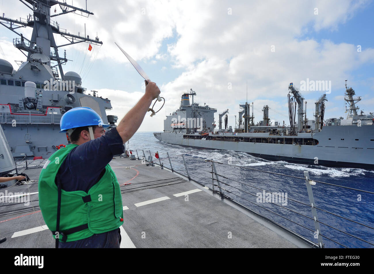 Seaman Mackeon Dudley signals the *USNS Leroy Grumman* (TAO 195) during ...