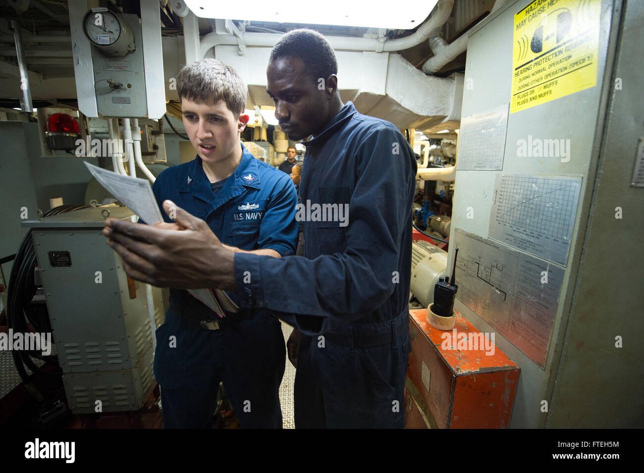 Gas Turbine System Technicians Shawn Flynn and Callistus Neba review an engineering manual ...