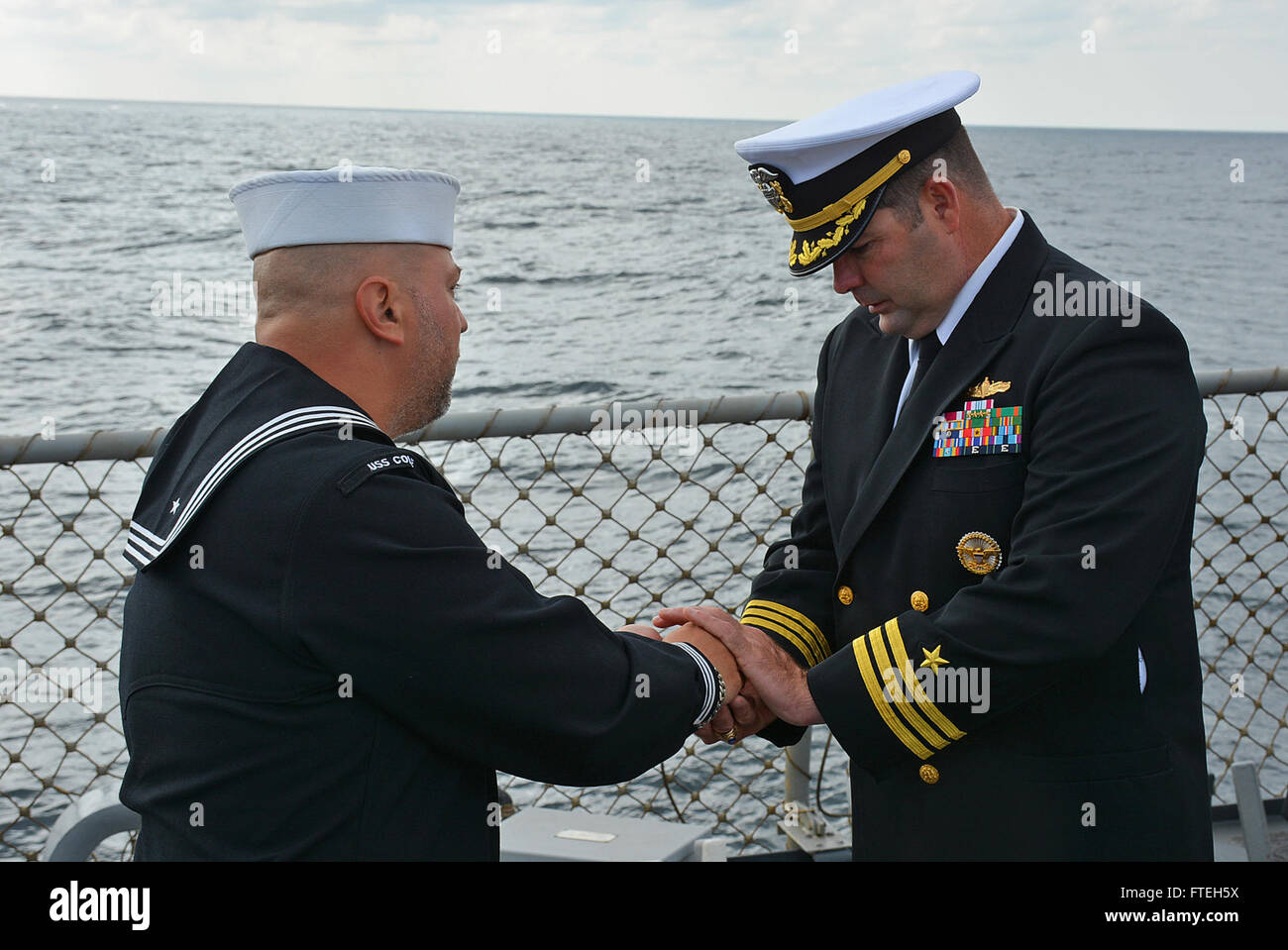 The photograph shows a somber memorial ceremony aboard the USS Cole ...