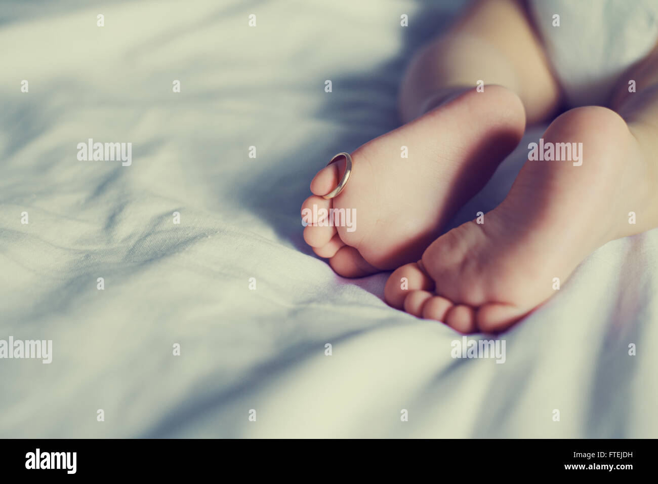 baby's feet with a golden ring on one of the toes, indoor shoot Stock ...