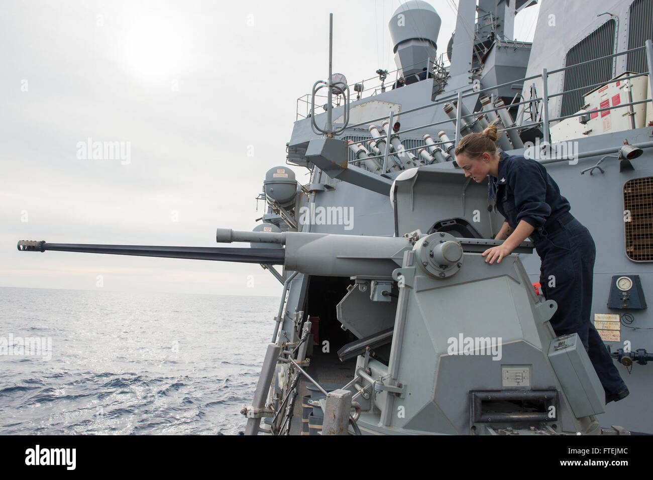 Gunner's Mate 3rd Class Rachael Beglan performs maintenance on the Mark 38 Mod 2 25mm machine ...