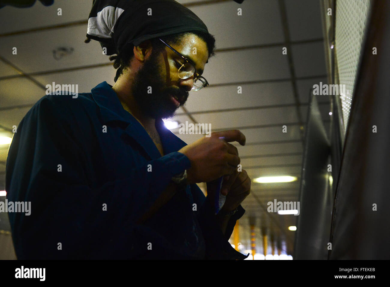 Fred Walker, a civil service mariner, conducts maintenance on the USS ...