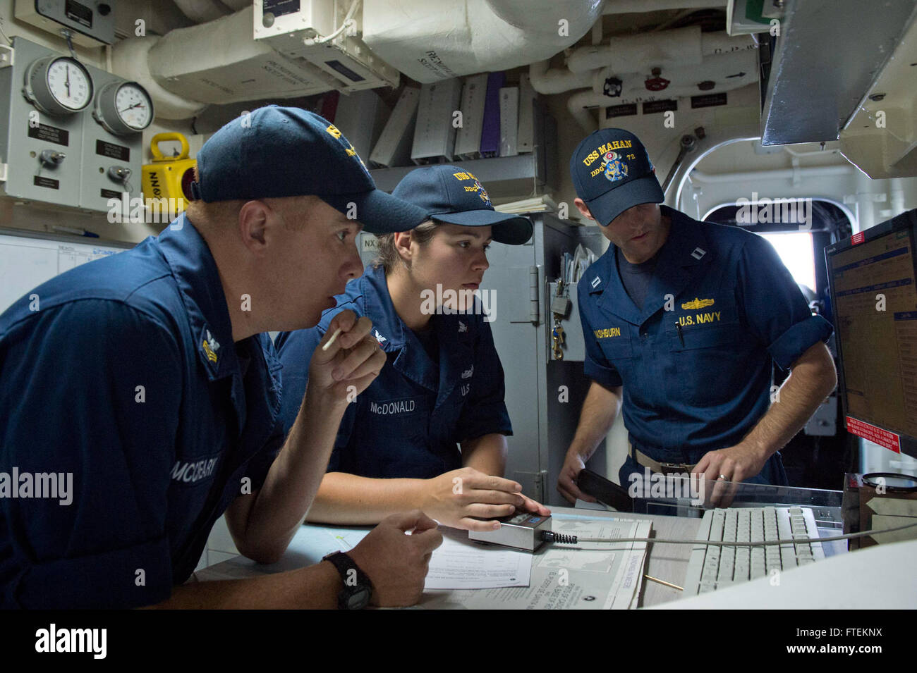 Sailors aboard the USS Mahan (DDG 72) review a planned navigational ...