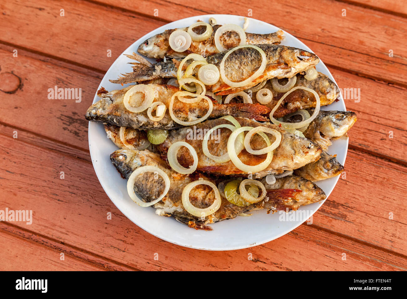 Fried fish with onion on the plate Stock Photo - Alamy