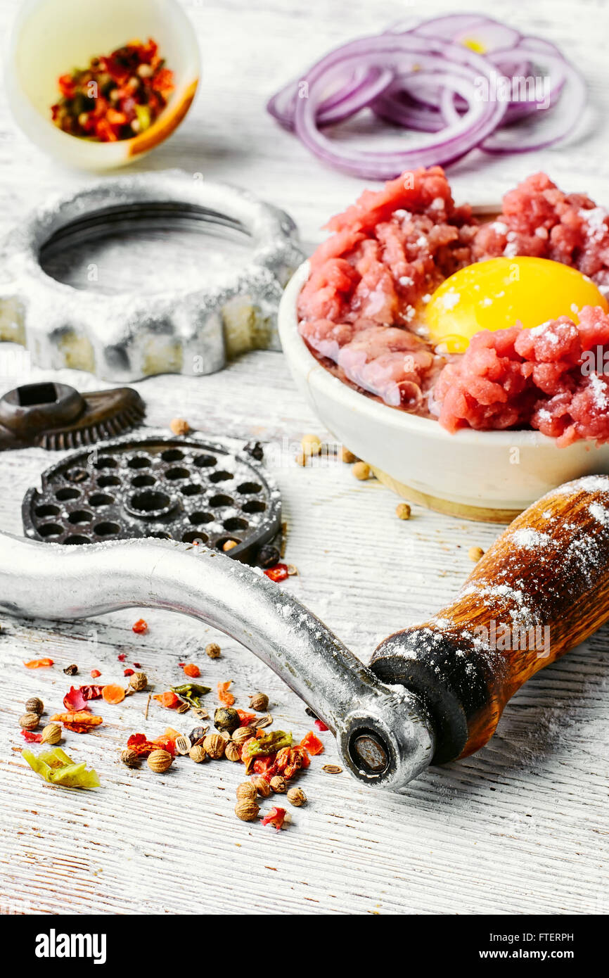 Dish of raw minced beef meat and parts of meat grinder Stock Photo - Alamy