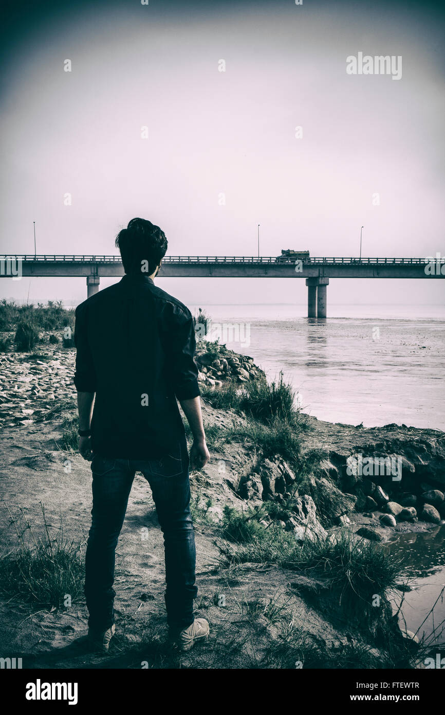 Male figure standing by the river Stock Photo - Alamy