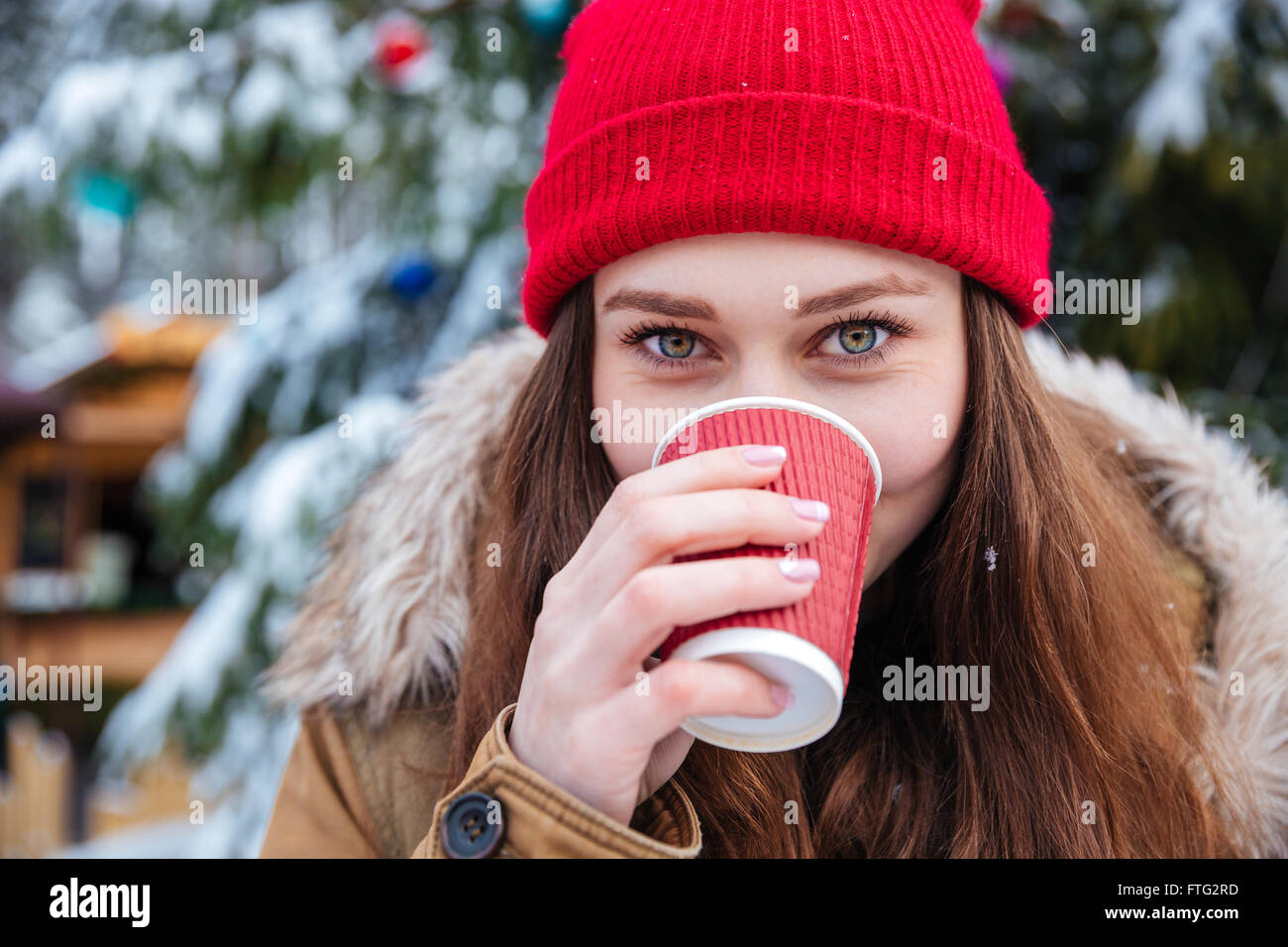 Closeup of cute lovely young woman in red hat drinking hot coffee ...