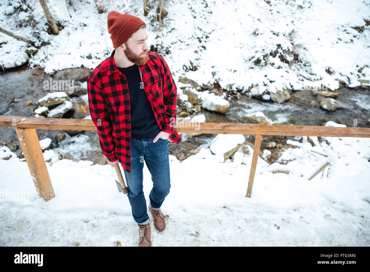 Top view of handsome thoughtful young man with axe standing and looking ...