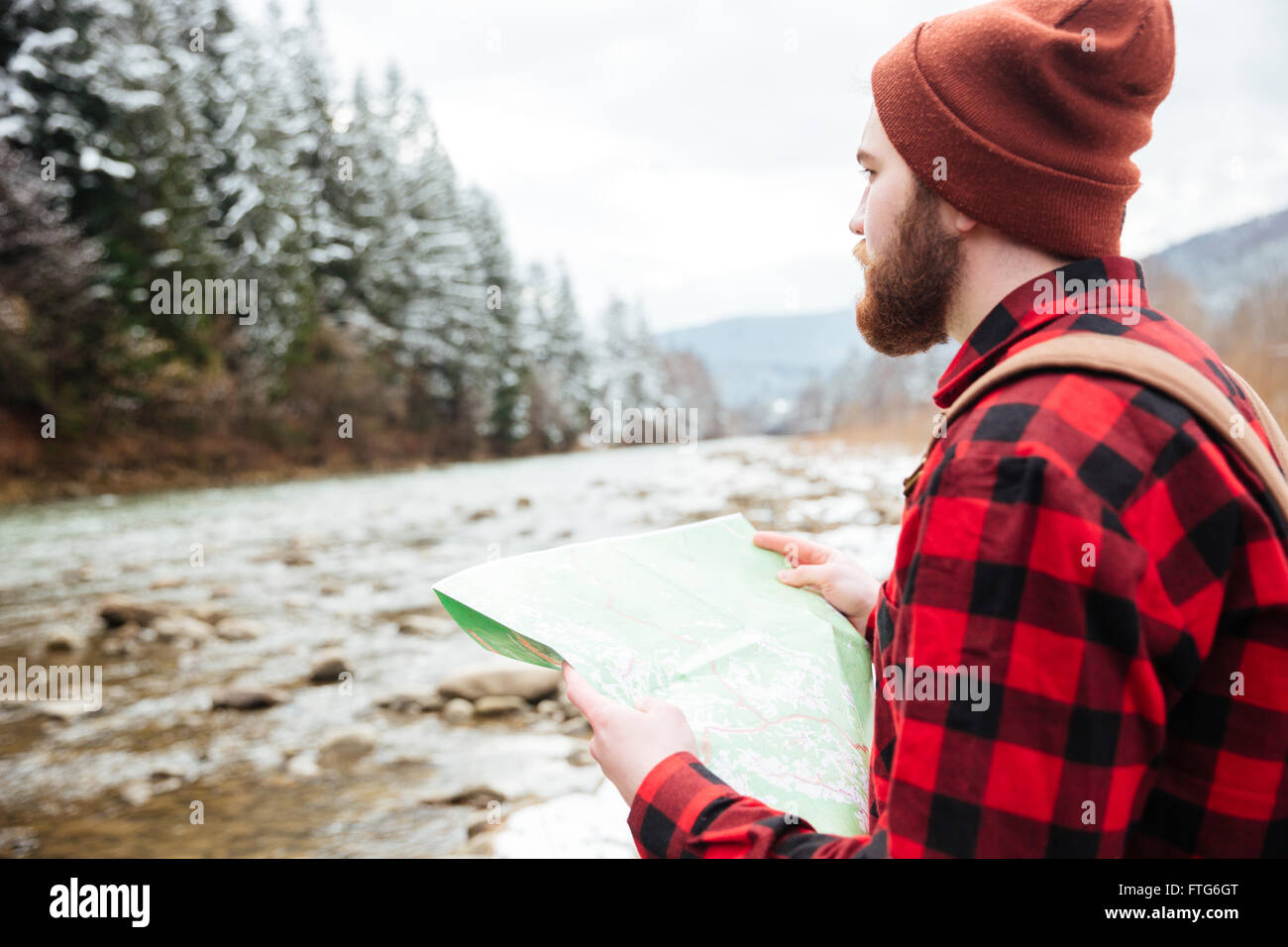 Male hiker holding map outdoors with river on background Stock Photo ...