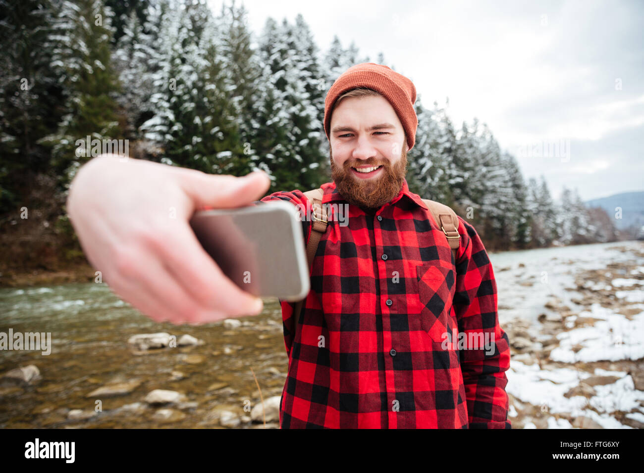 Smiling man doing selfie photo outdoors with forest and river on ...