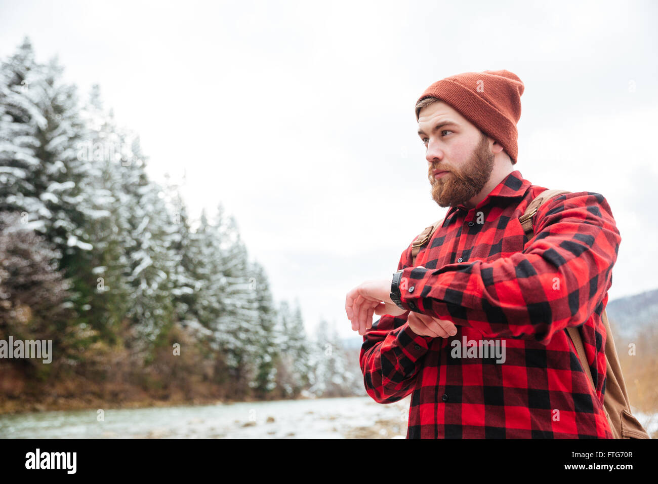 Handsome man standing outdoors and looking away with forest on ...