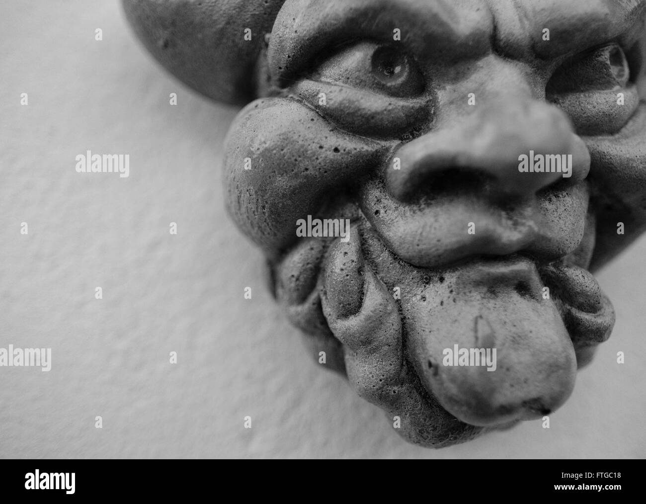 Stonework gargoyle face seen hanging on a garden wall Stock Photo - Alamy