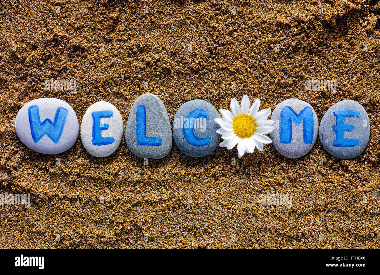 Word Welcome spell out from stones with letters and flower on sea sand ...