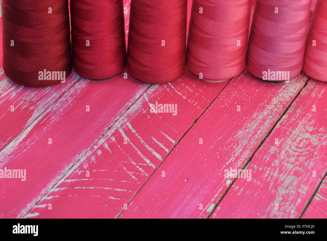thread red and pink colors for sewing and embroidery on pink wooden ...