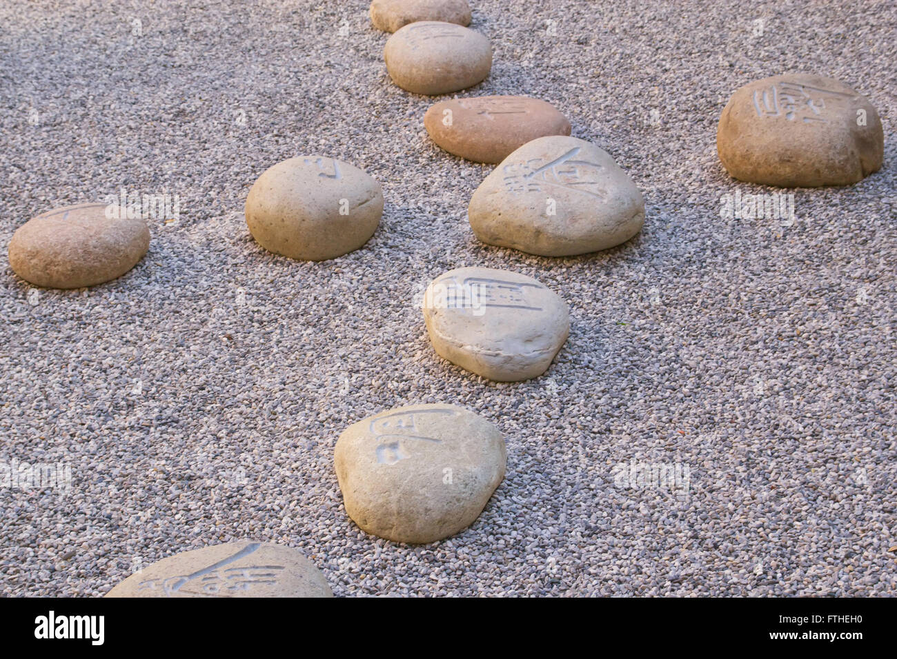 Boulders carved with Chinese characters lying in the gravel. The stones ...