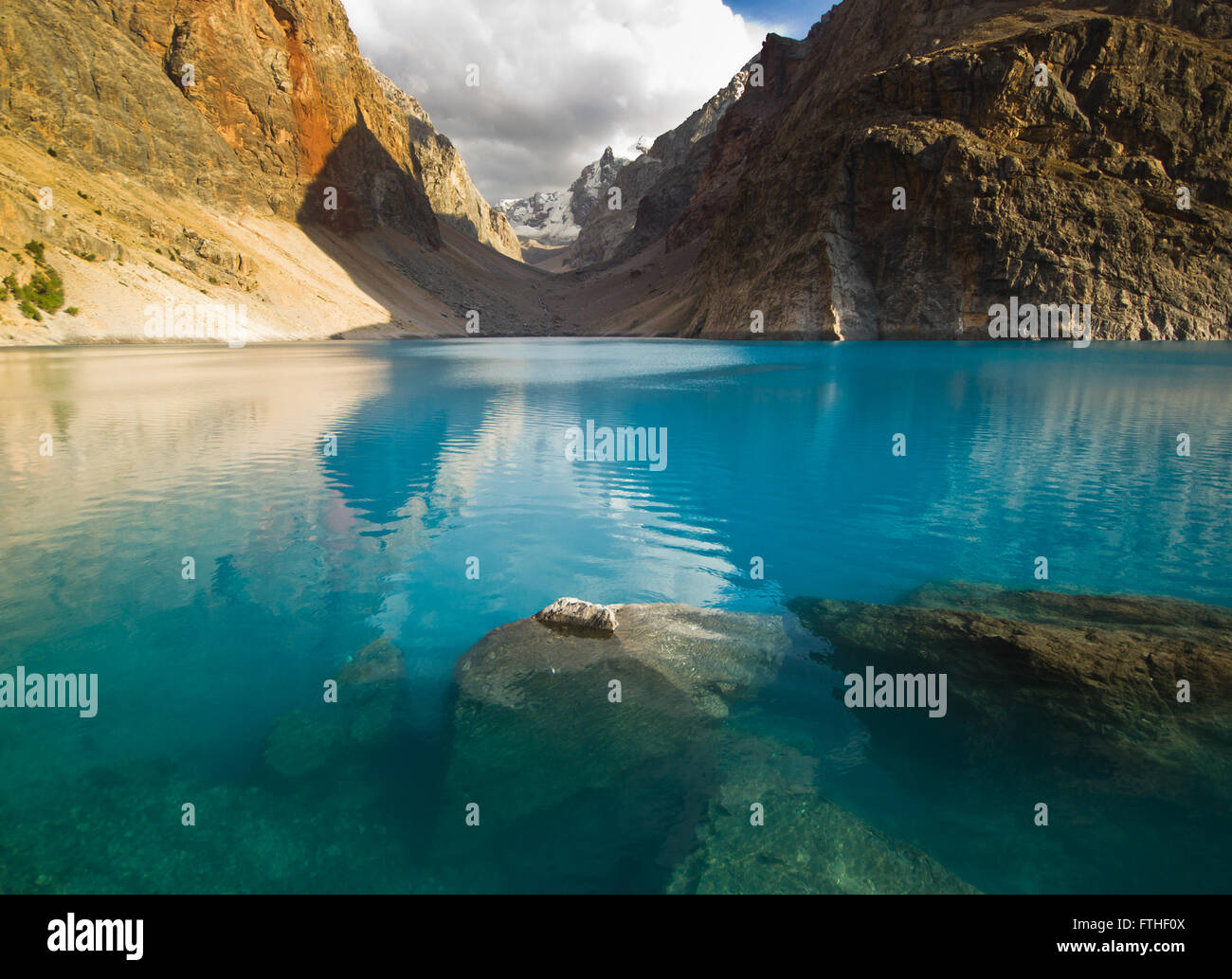 deep blue mountain lake at sunrise surrounded by high peaks Stock Photo ...
