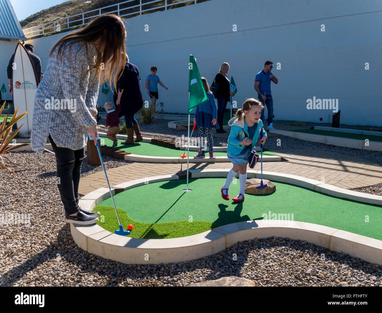 Two girls playing on a mini golf course on seaside promenade at ...