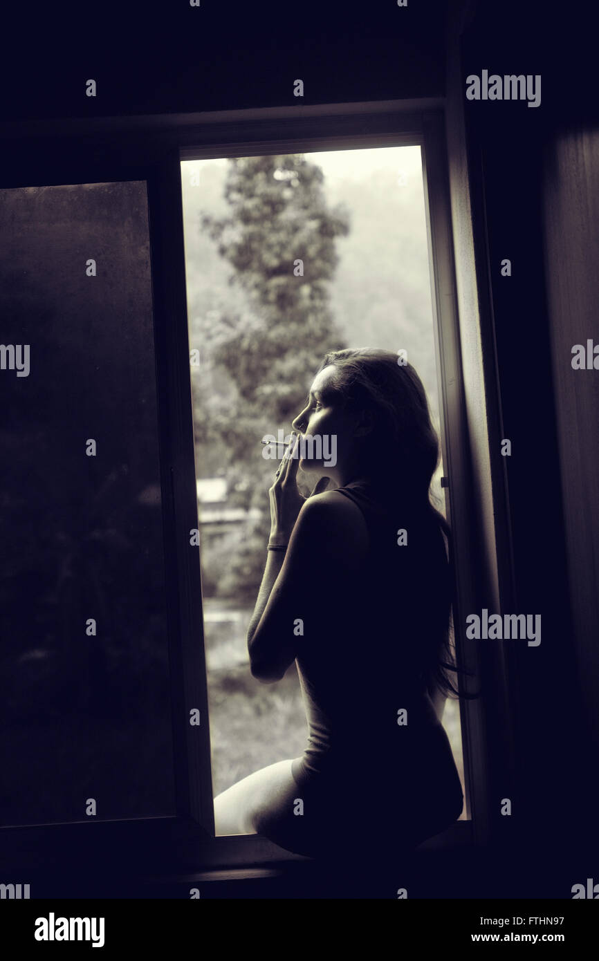 Woman smoking by window hi-res stock photography and images - Alamy