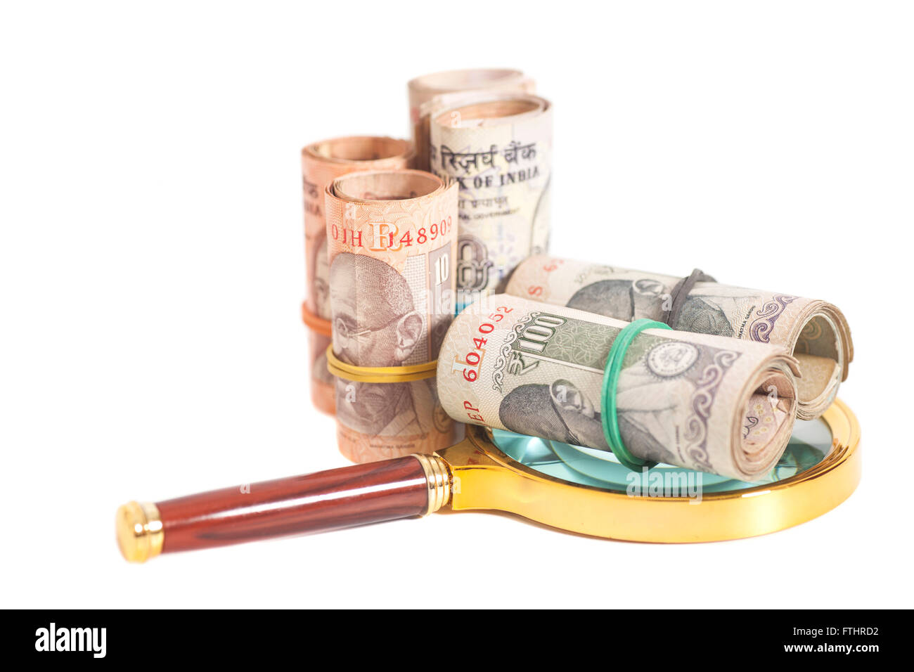 Rolls of Indian Currency Rupee Notes with magnifying glass on white ...