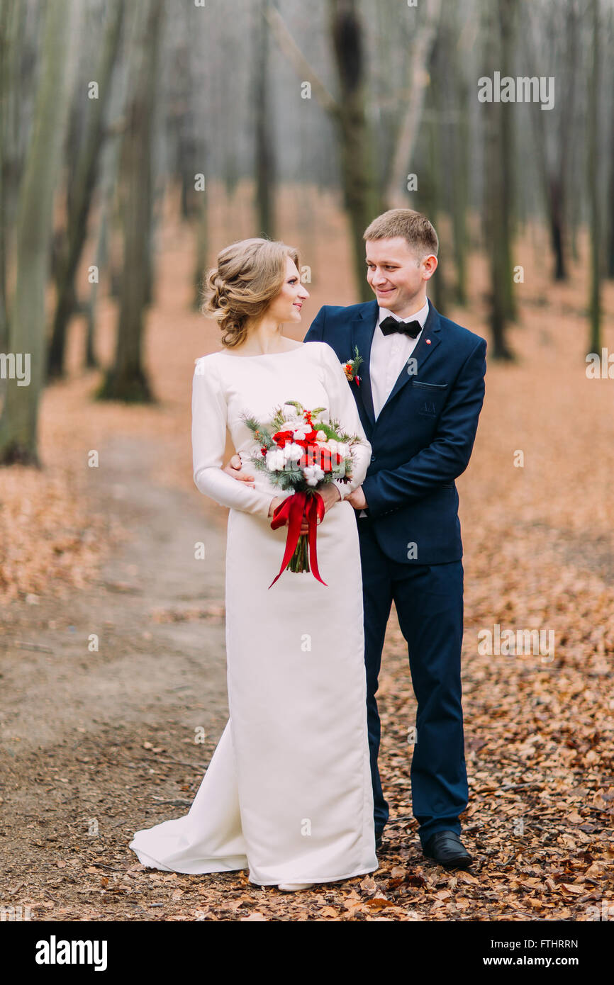 Handsome groom and beautiful bride lovingly look at each other in the ...