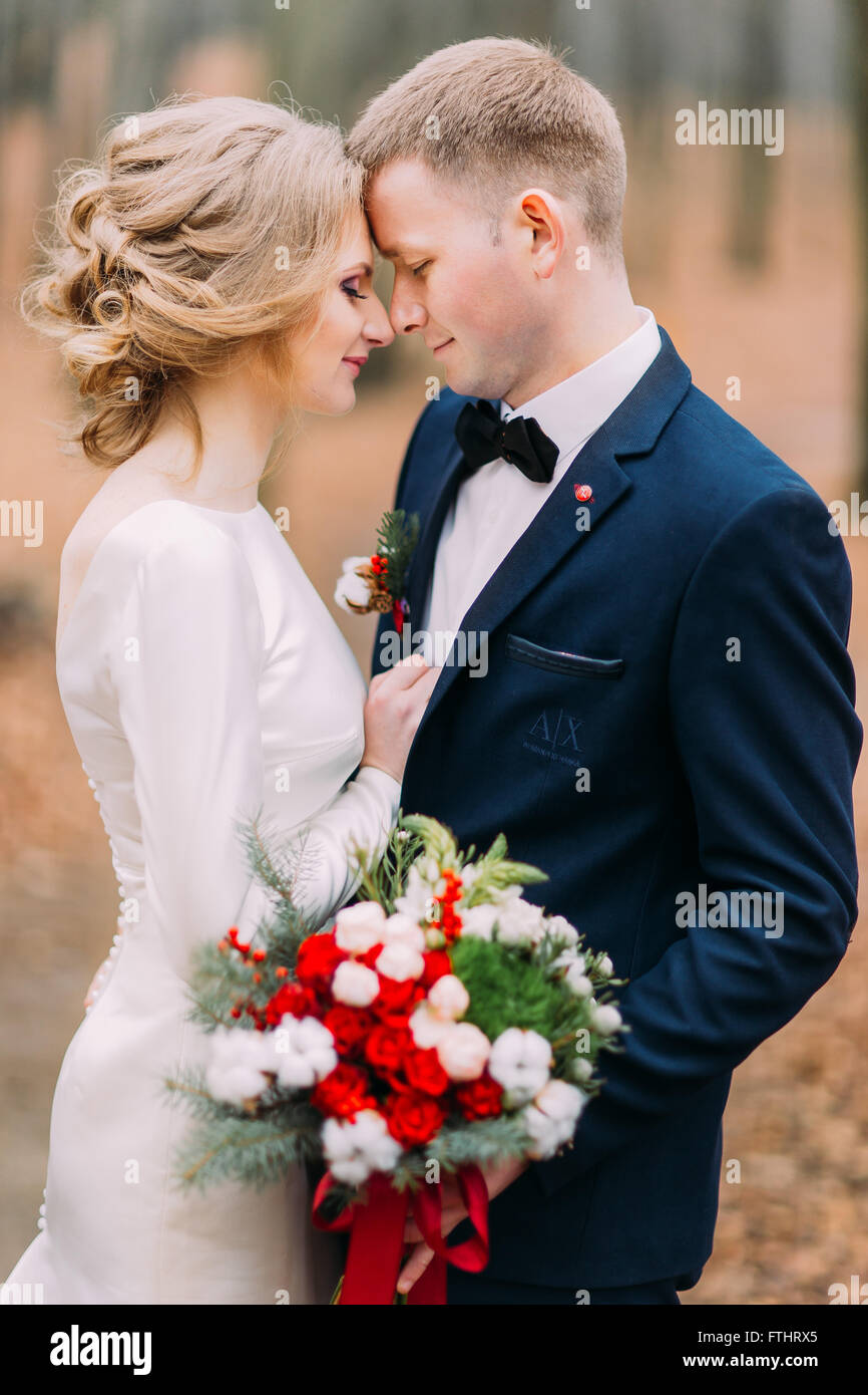 Handsome groom and beautiful bride lovingly look at each other in the ...