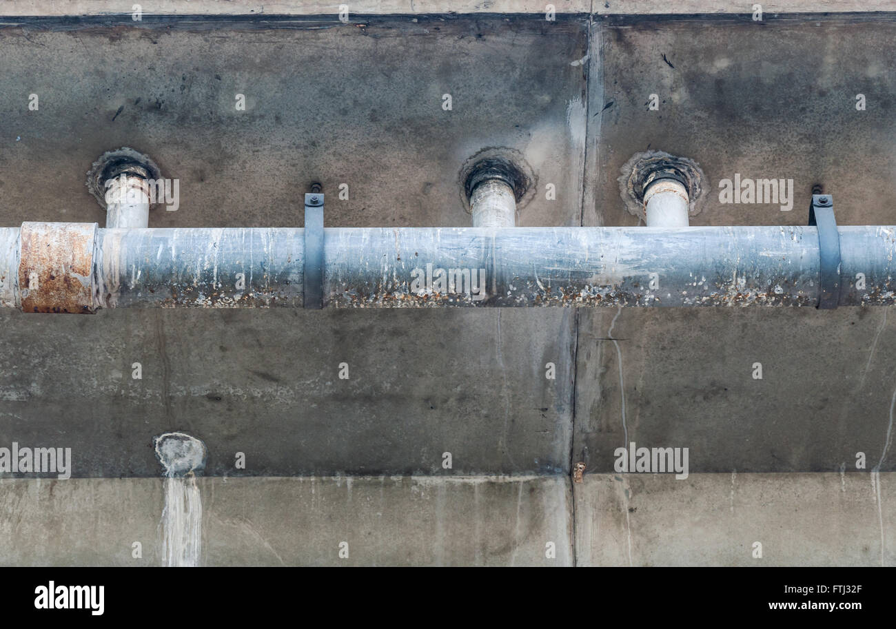 Rusty metal drain is hanging under the road bridge Stock Photo - Alamy