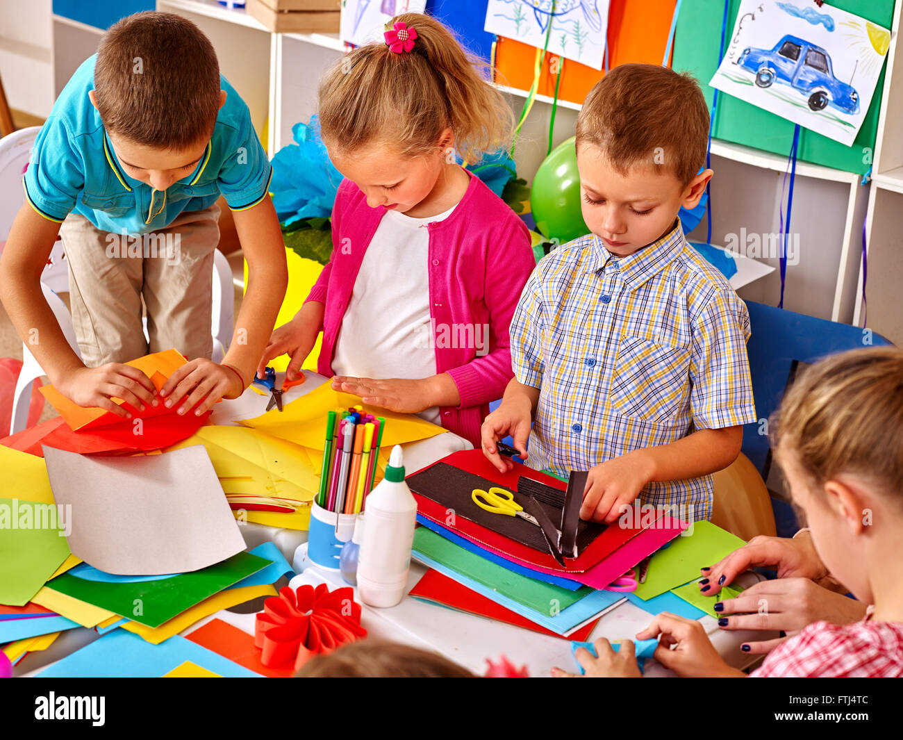 Kids holding colored paper on table in kindergarten Stock Photo - Alamy