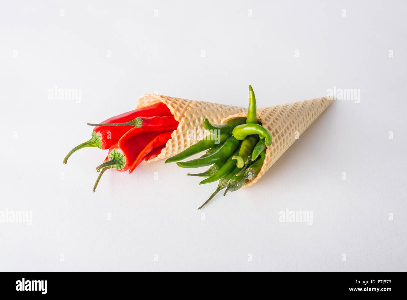 Red and green hot chili peppers in wafer cones on white background ...