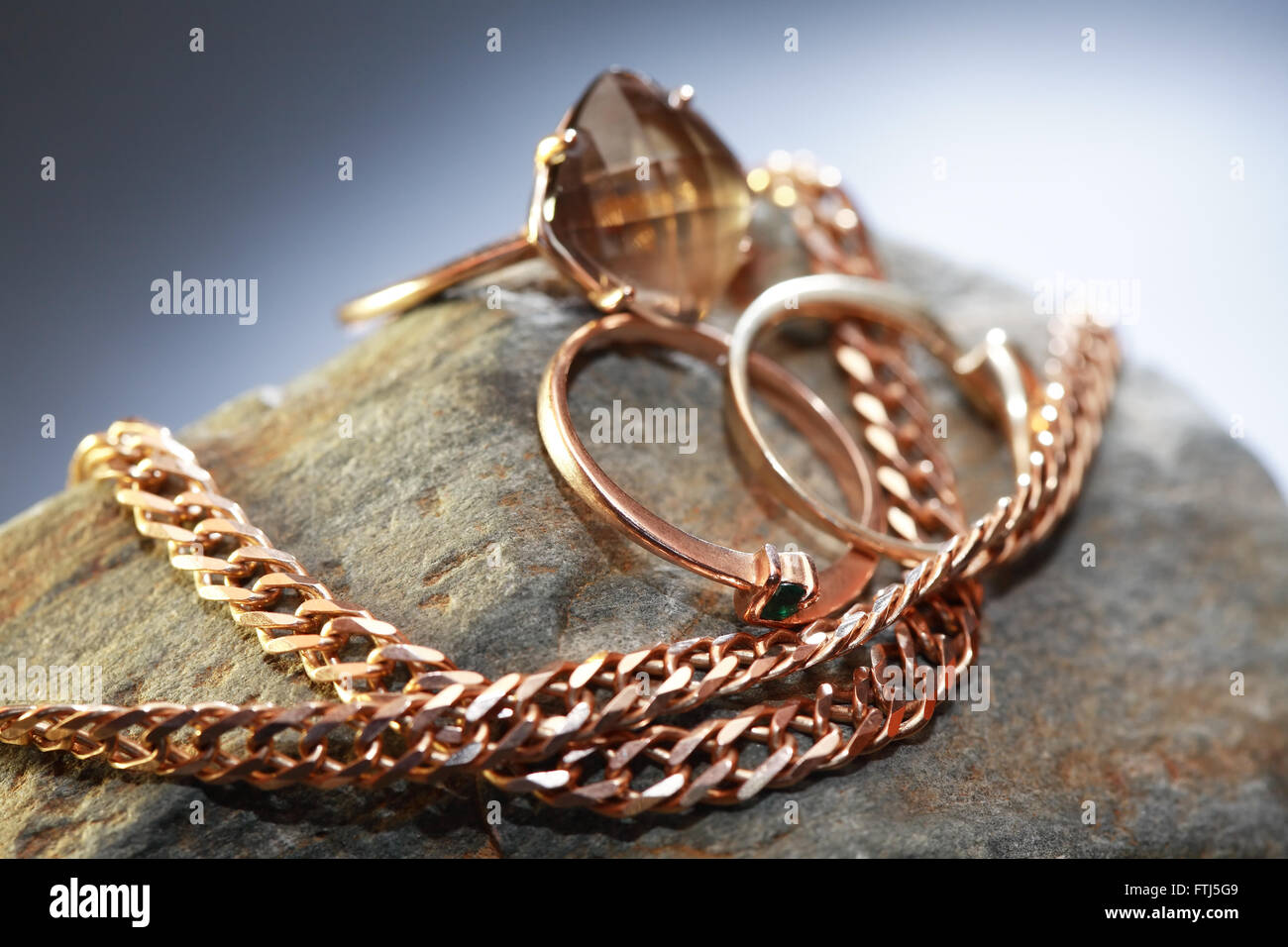 Gold rings and chain on gray stone against nice dark background Stock ...