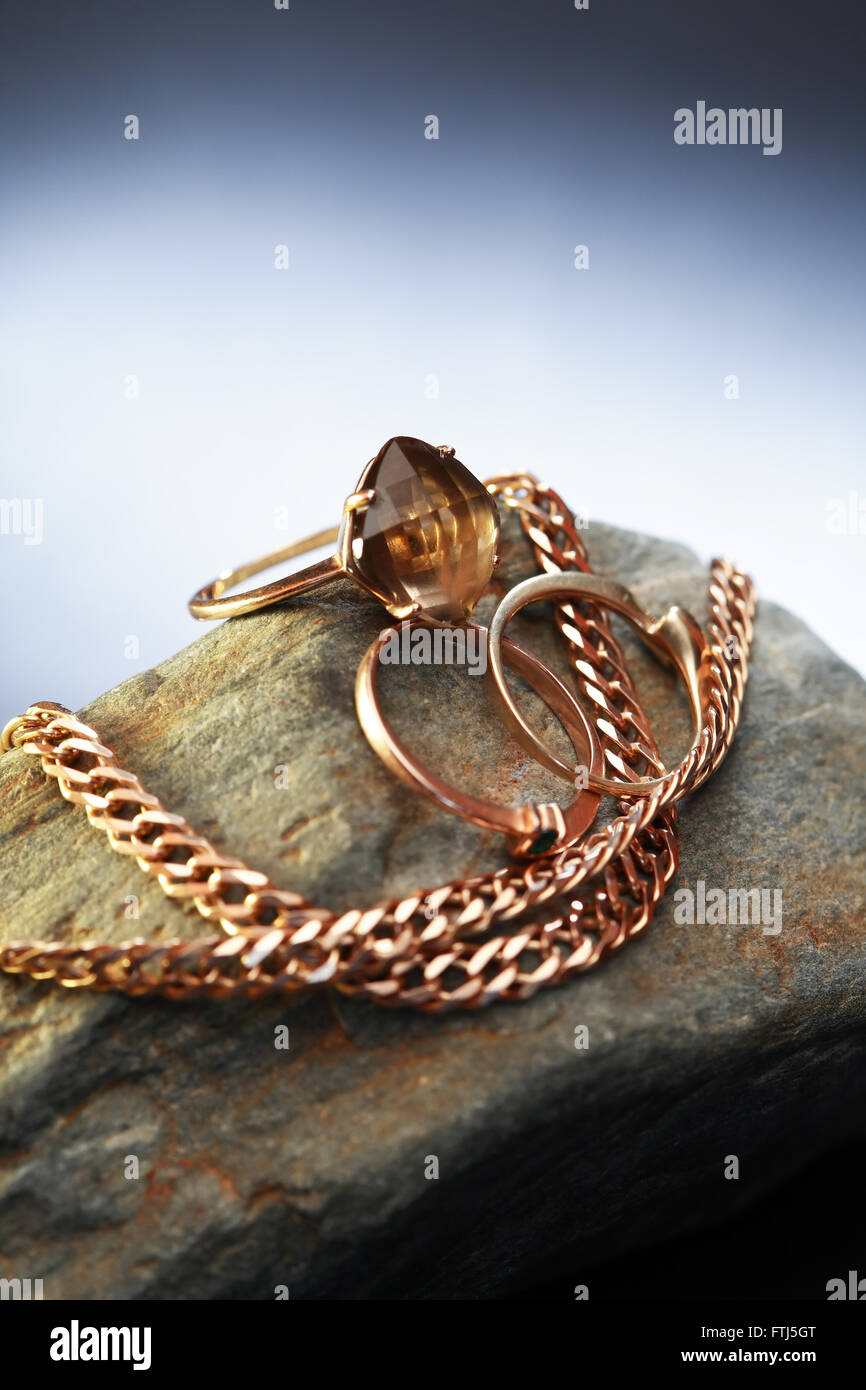Gold ring and chain on gray stone against nice dark background Stock ...