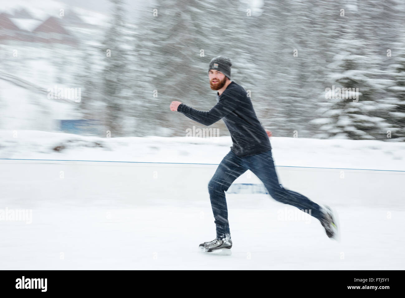 Handsome man ice skating outdoors with snow on background Stock Photo ...