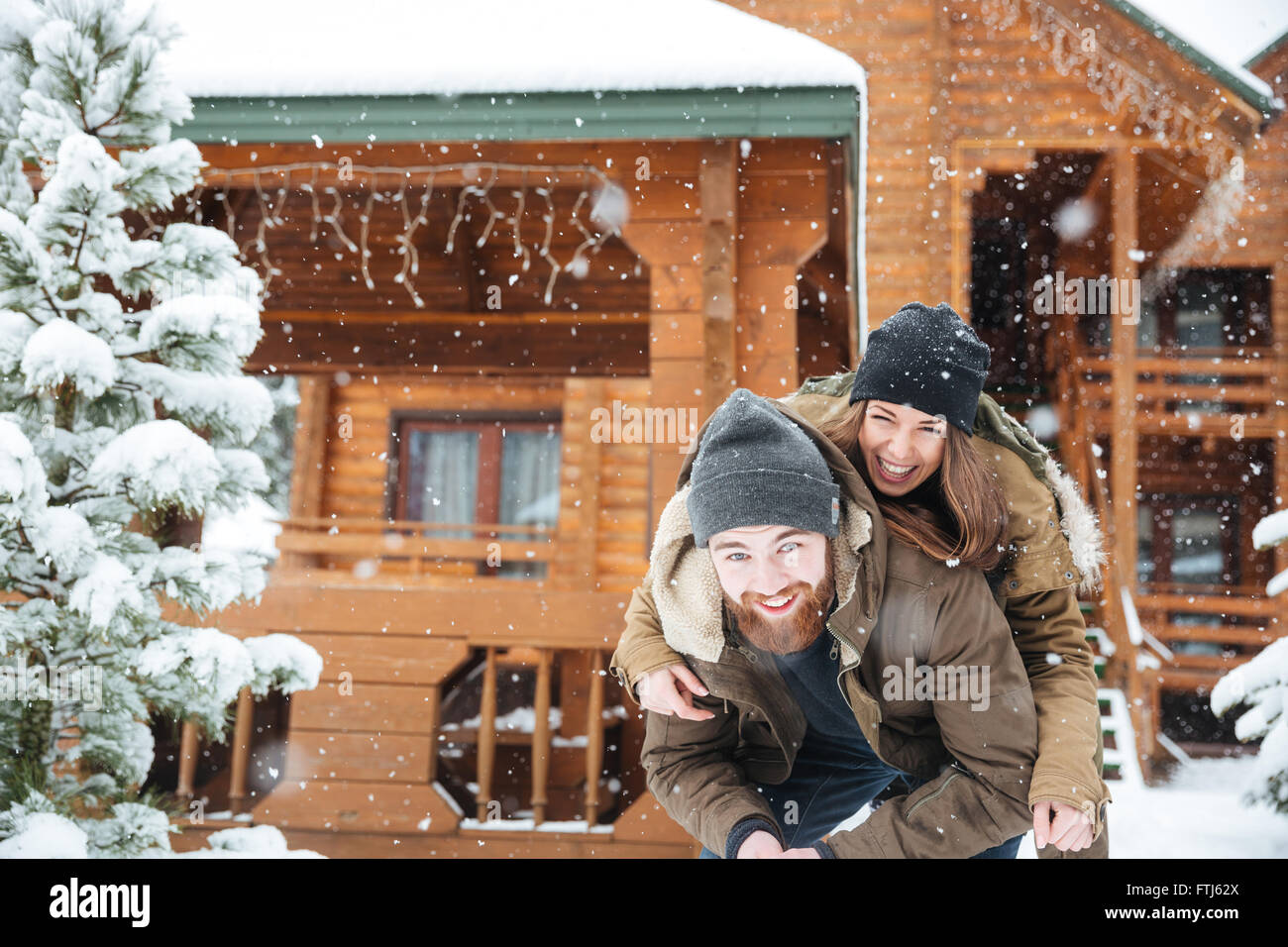 Beautiful cheerful young couple having fun in front of log cabine in ...