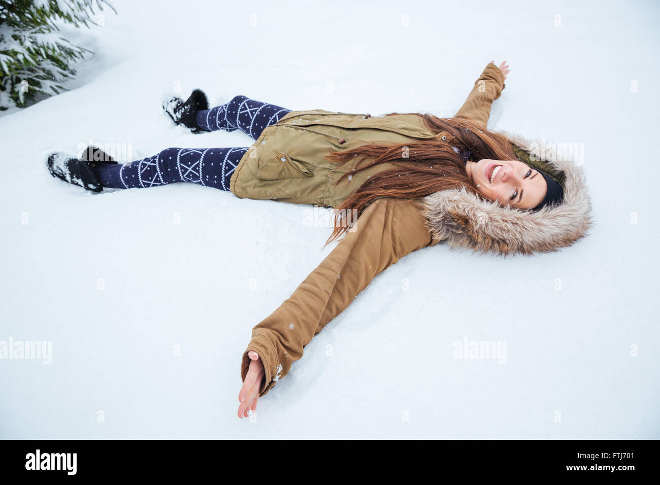 Cheerful pretty young woman lying on snow outdoors in winter Stock ...