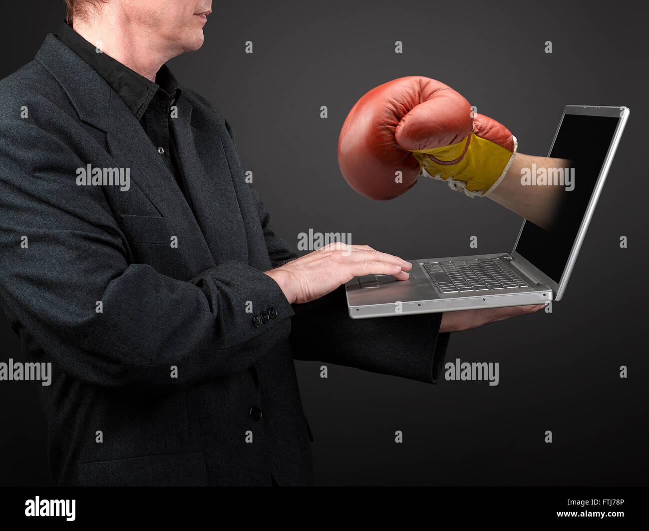 Man in black shirt and suit holding a laptop and win Boxing glove punch ...