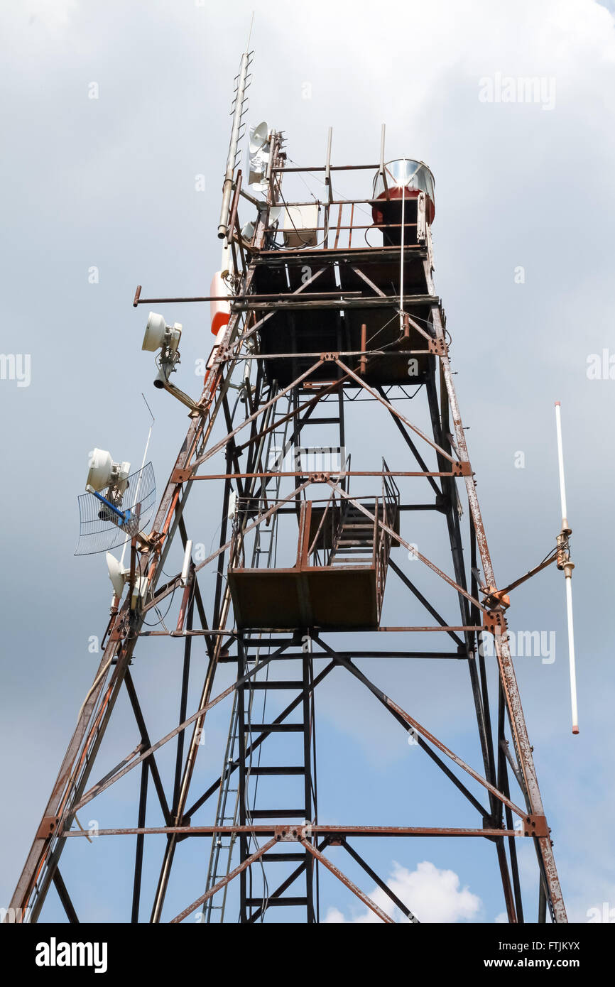 Telecommunication radio tower with different transmitters and receivers devices above cloudy sky ...