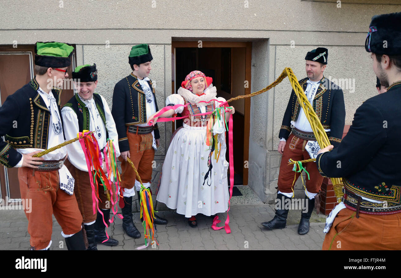Young men in folk costume whip a girl with plaited willow stems during ...
