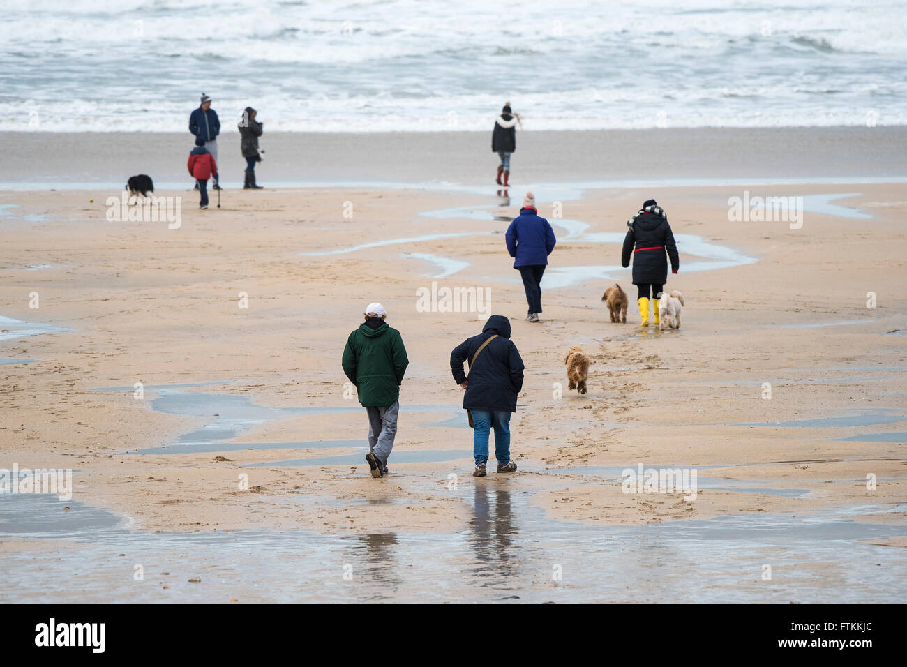 People enjoy a brisk walk on a cold, windy day at Fistral Beach in ...
