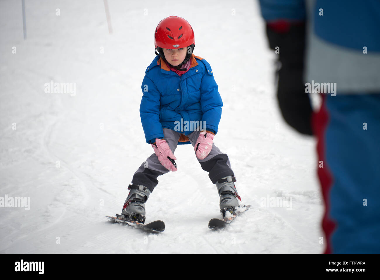 Child skiing in the mountains. Girl with safety helmet learning to ski ...