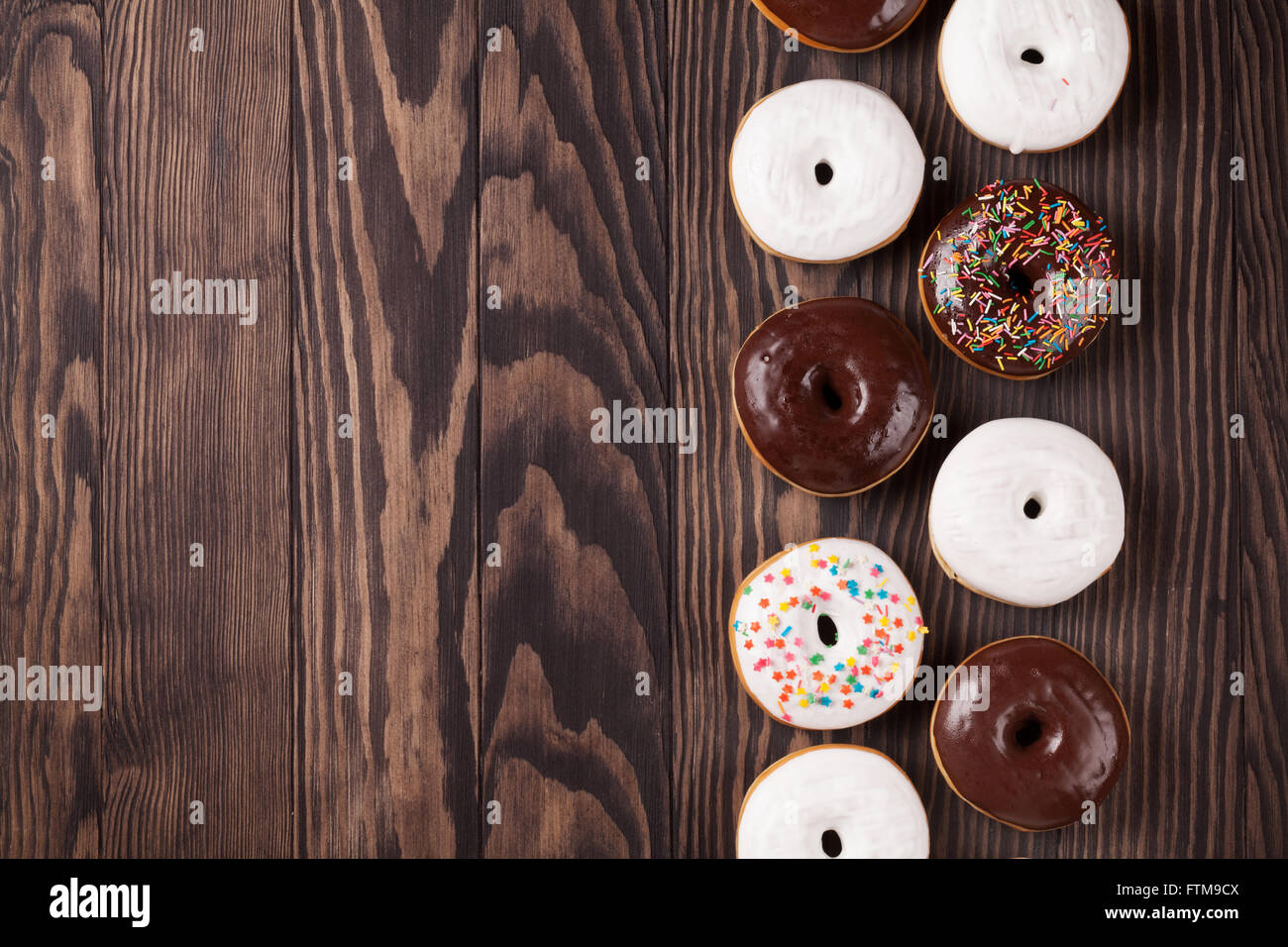 Donuts with colorful decor on wooden table. Top view with copy space ...