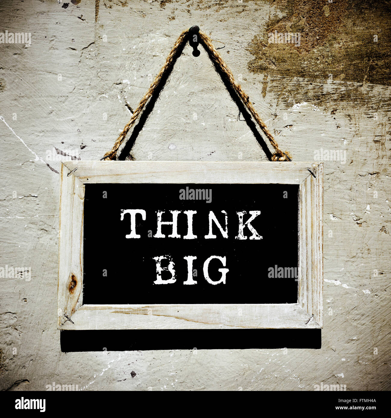 an aged chalkboard with the text think big hanging on a nail on a ...