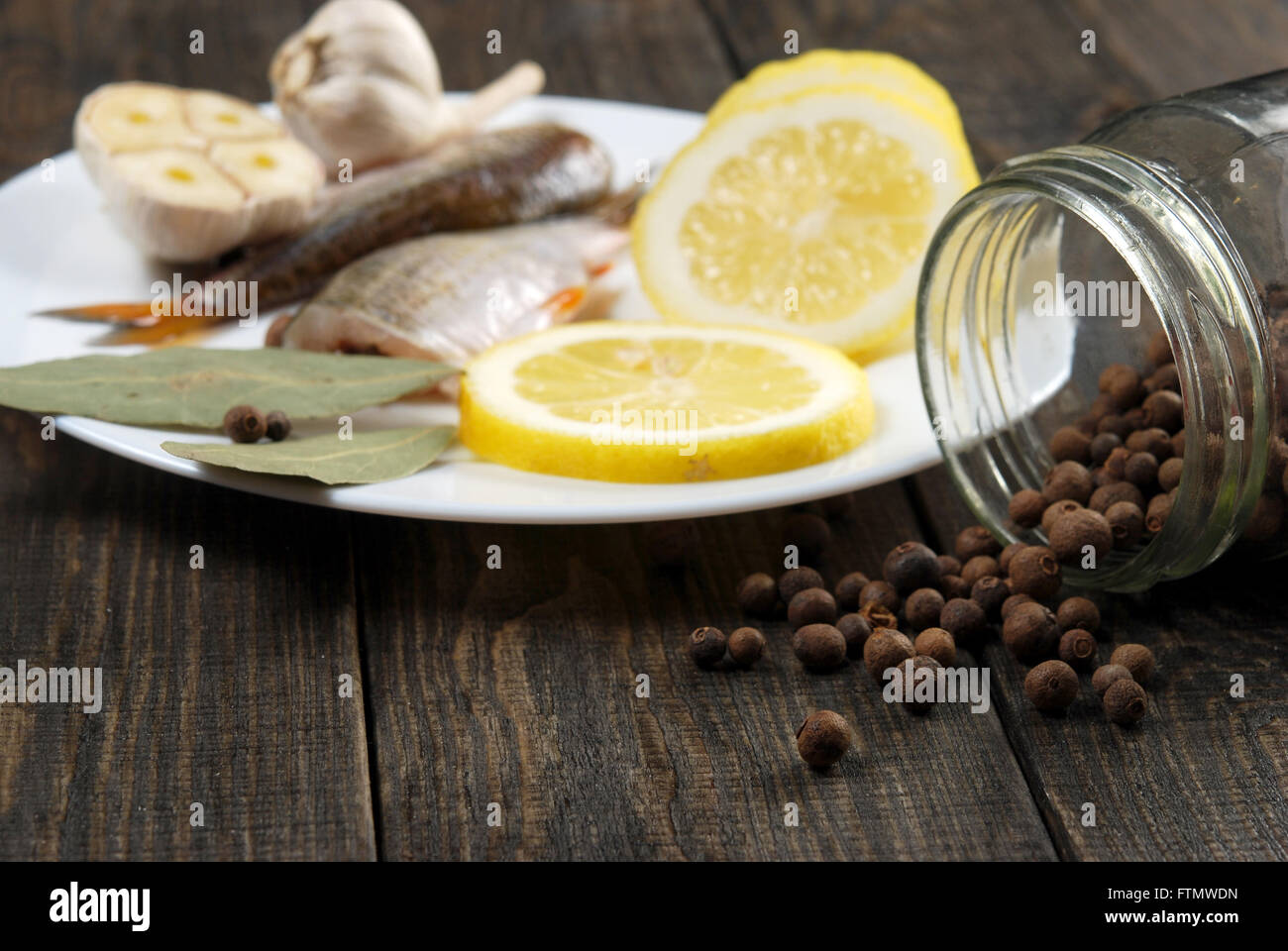 Round pepper, pours out of the jar, raw fish with lemon, garlic, and ...