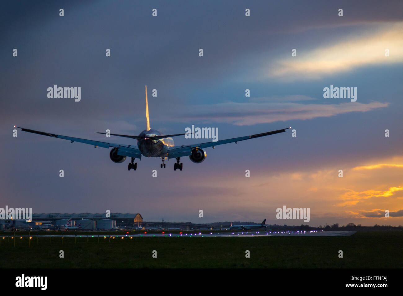 A British Airways Boeing 777-300 lands as the sunset illuminates the ...