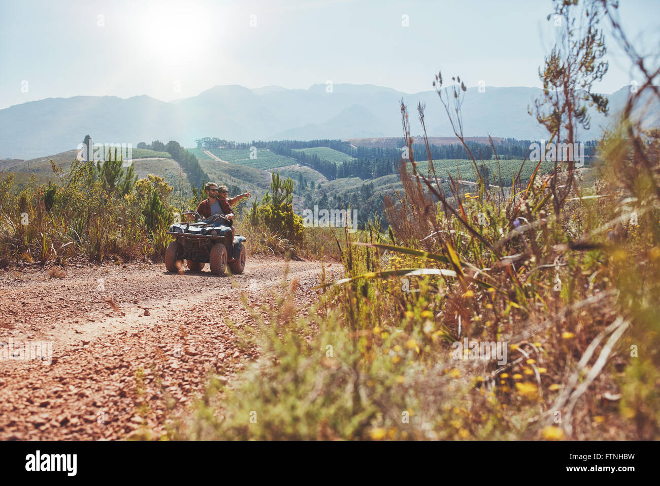 Young couple having fun on quad bike ride on a summer day. Young man ...