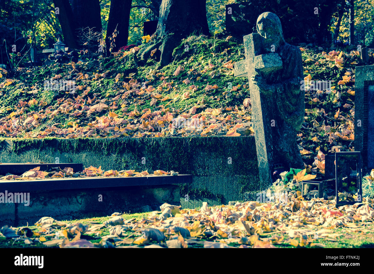 old stone statue of saint with cross in the cemetery Stock Photo - Alamy