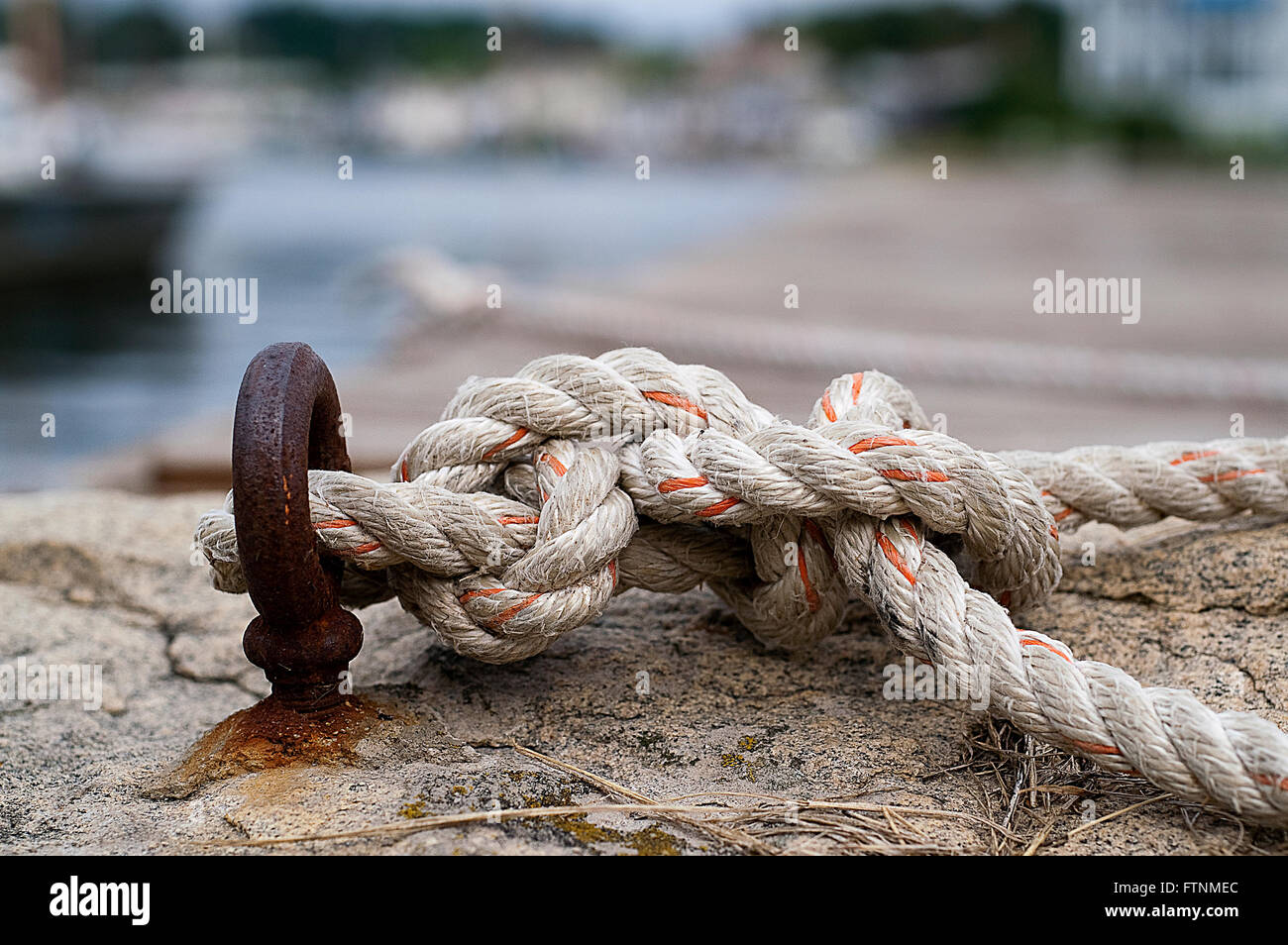 Rope tied with nautical knot, with blurry harbor visible in the ...