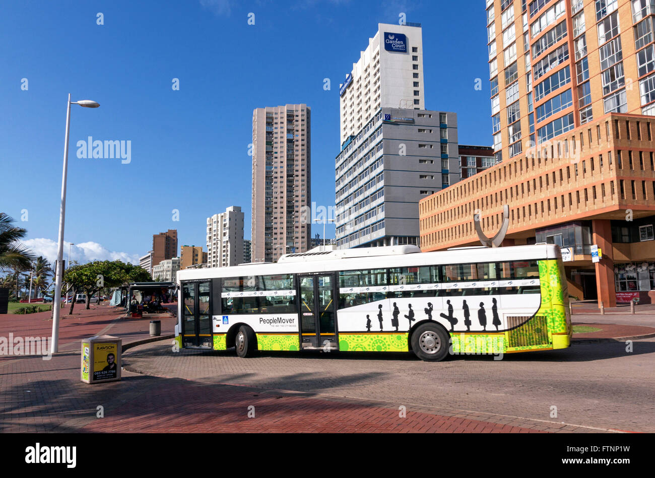 Municipal bus navigating through roundabout against city skyline on ...