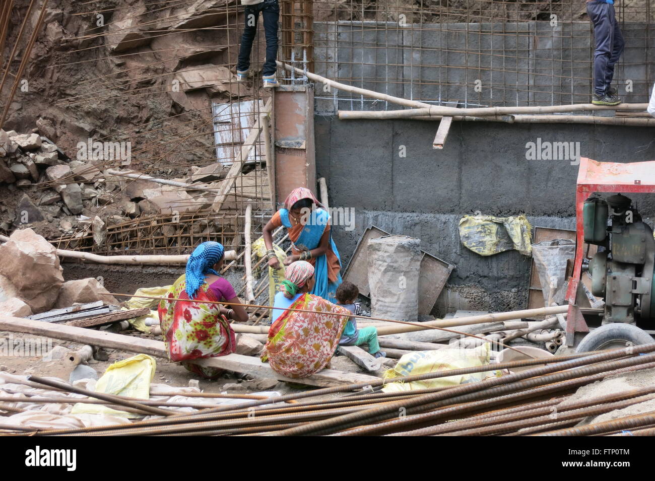 Three Indian woman in bright sari's and a child crouch on a pile of ...