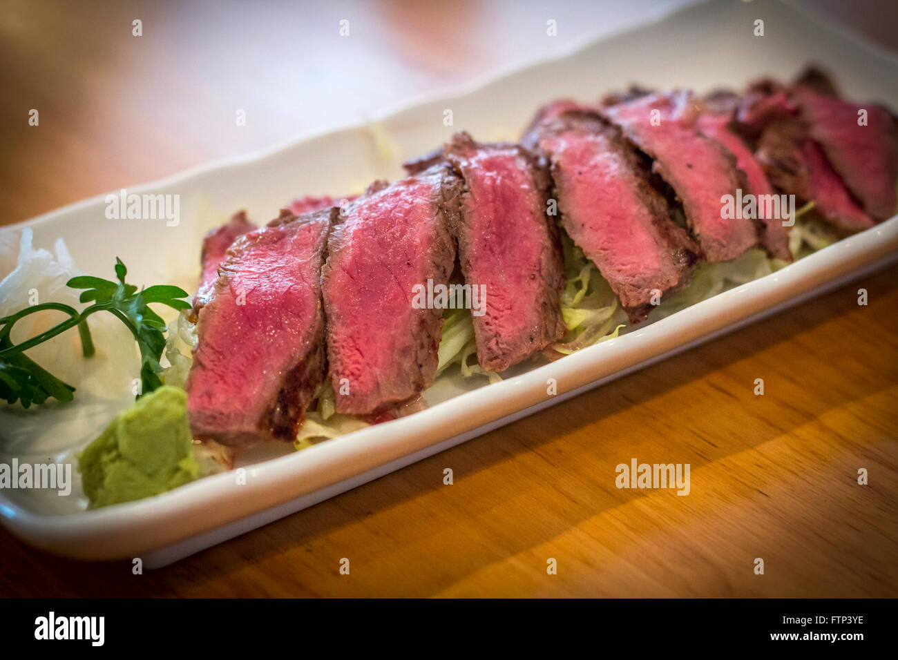 Japanese seared beef tataki served rare on bed of shredded lettuce ...