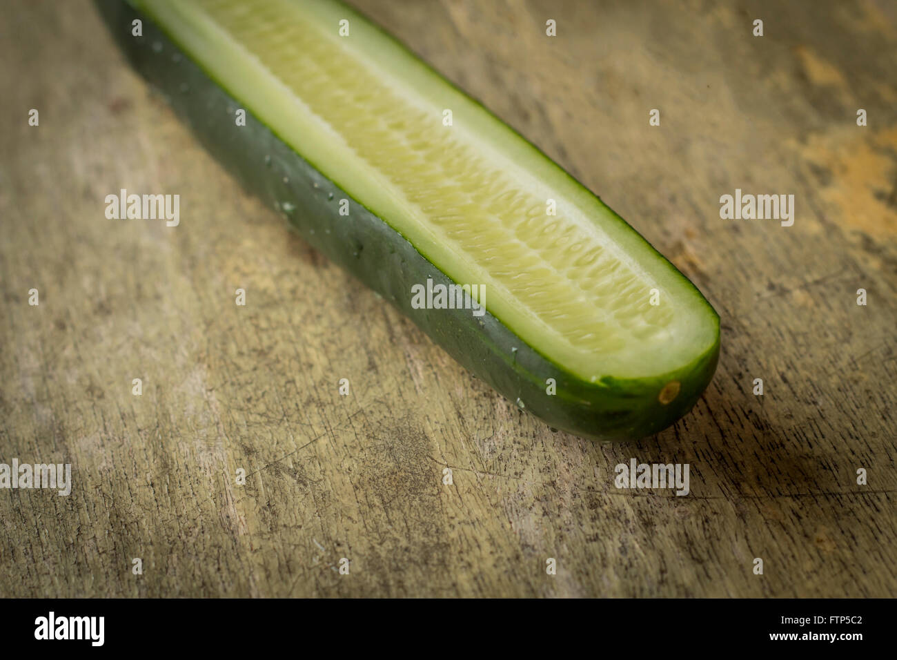 Cucumber sliced lengthwise with seeds on grungy wooden table Stock ...